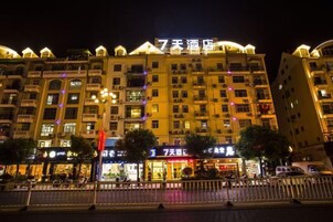 Um hotel de vários andares com sinalização iluminada e varandas.