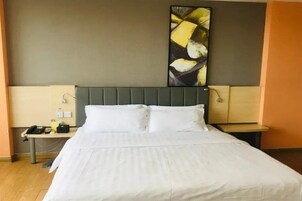 Quarto de hotel com uma cama grande, cabeceira, mesas de cabeceira e um quadro na parede.
