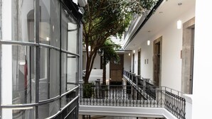 Área externa coberta com grade de metal, uma árvore e escadas que levam a um andar superior.