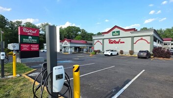 Um Red Roof Inn com estacionamento, posto de gasolina e placa Home Towne Studios.