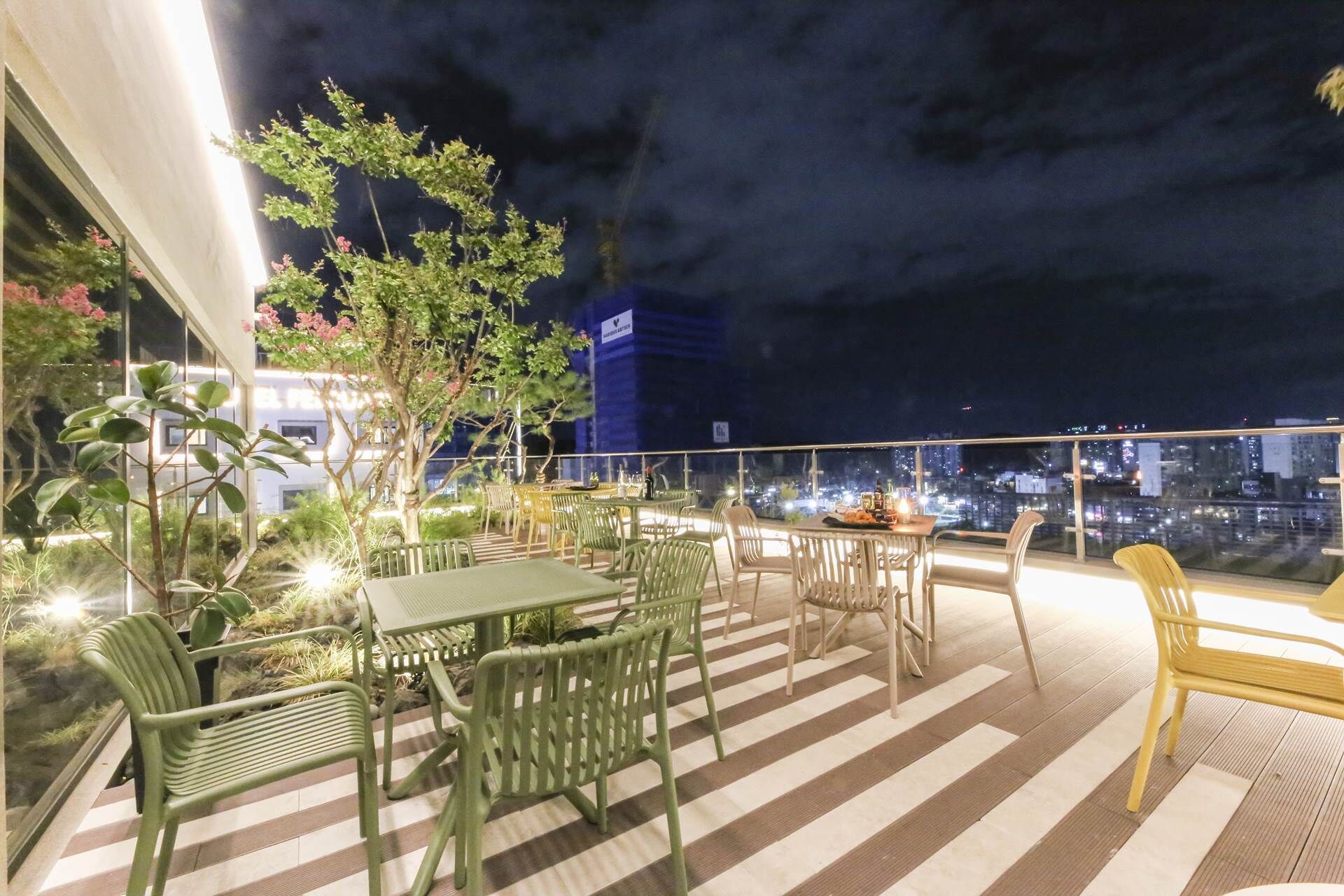 Um terraço no telhado com mesas ao ar livre, vista para a cidade e um edifício ao fundo.