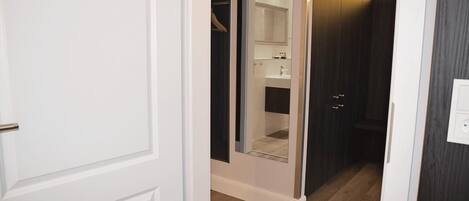 Um corredor com uma porta branca, um armário com espelho e uma parede de madeira escura.