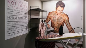 Pessoa a passar roupa numa tábua de passar com um guia na parede.