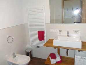 Casa de banho com lavatório, espelho e porta-toalhas.