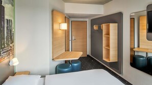 Quarto de hotel moderno com cama, escrivaninha e espelho.