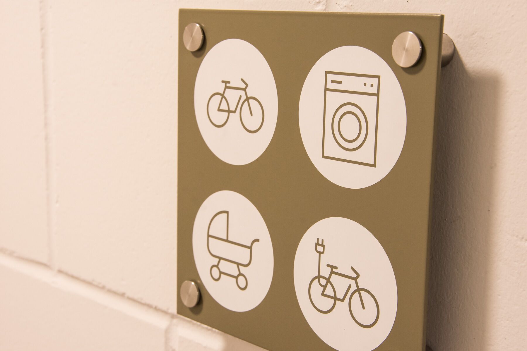 Um sinal com quatro ícones: uma bicicleta, uma máquina de lavar, um carrinho de bebê e uma bicicleta com tomada.