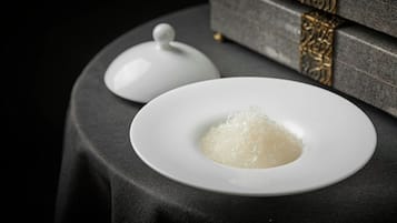 Um prato branco com uma substância branca sobre uma toalha escura.