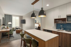 Cozinha moderna com ilha central, armários de madeira e micro-ondas embutido.