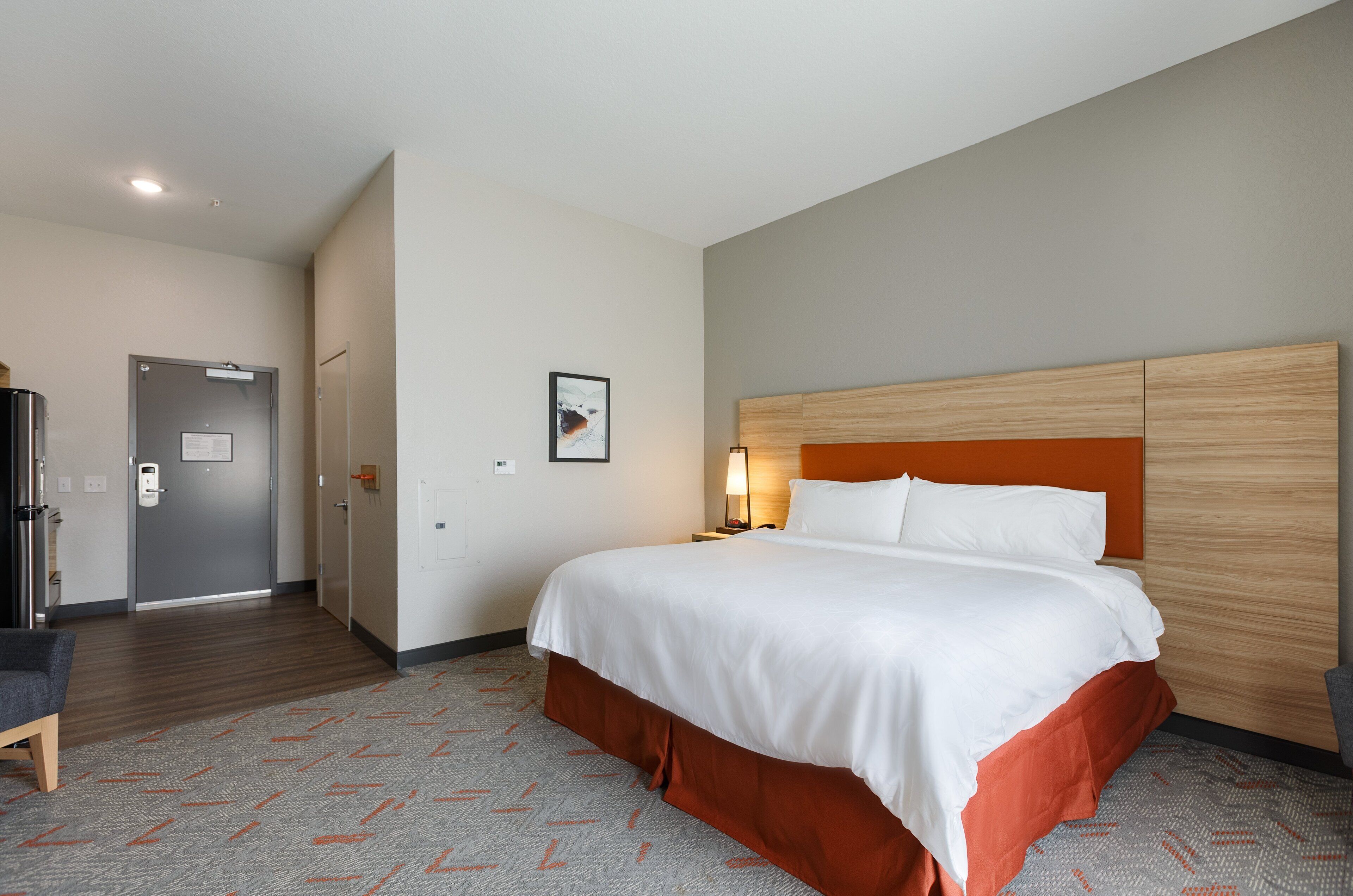 Quarto de hotel com uma cama grande, uma escrivaninha e uma cadeira.