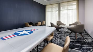 Uma sala de conferência com uma mesa grande adornada com um emblema de estrela, cadeiras bege e carpete escuro.