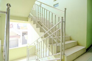 Escada com corrimãos e guarda-corpo, conduzindo a um andar superior.