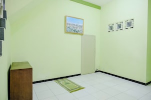 Um quarto com piso de azulejos, um quadro na parede e um pequeno pódio de madeira.