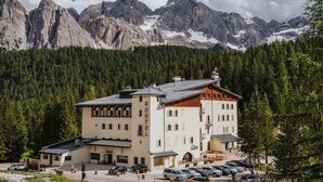 Um hotel com montanhas ao fundo, área de estacionamento e um edifício com uma placa.