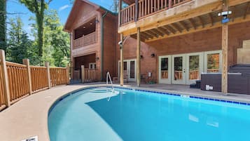 Uma cabana de madeira com piscina, varanda e deck.
