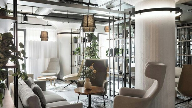 Um interior moderno com um sofá, poltronas, uma mesa redonda e um grande pilar branco.