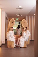 Um espaço de spa moderno com bancos de madeira e uma pessoa vestindo um roupão.