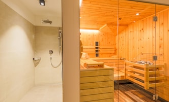 Uma sala de sauna com bancos de madeira e divisória de vidro.