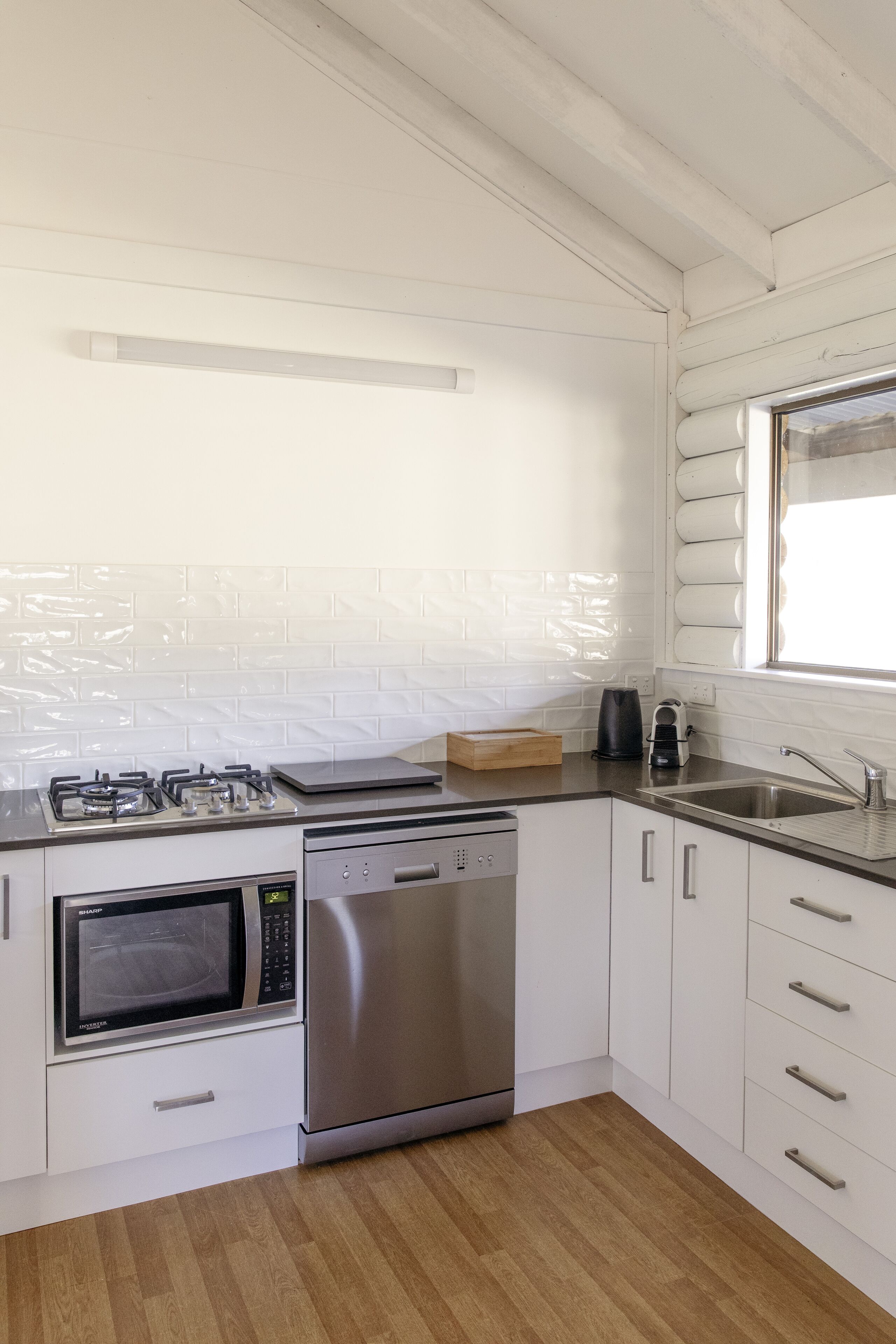 Uma cozinha moderna com armários brancos, eletrodomésticos de aço inoxidável e piso de madeira.