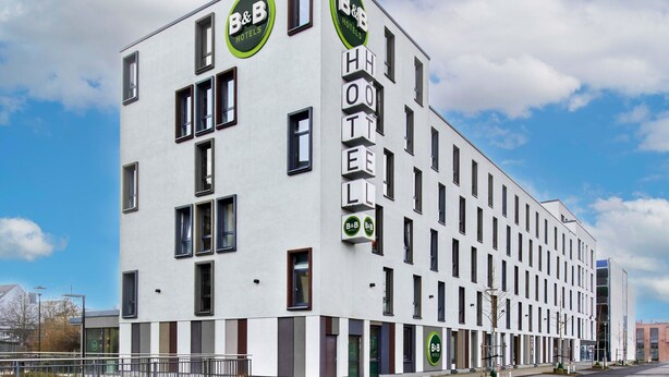 Um moderno edifício de B&B hotel com fachada branca, várias janelas e logotipos B&B.