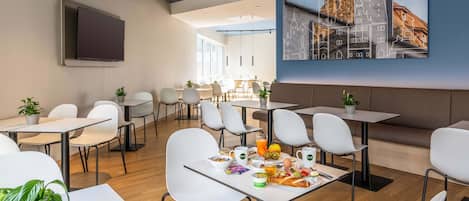 Uma sala de jantar moderna com cadeiras e mesas brancas, um quadro grande com vista da cidade e uma televisão na parede.
