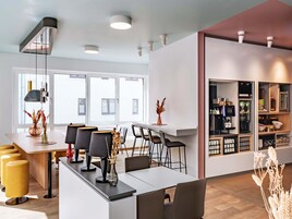 Uma área de refeições moderna com uma mesa comprida, várias cadeiras e um balcão de bar.