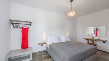 Quarto com cama, mesas de cabeceira, luminária pendente, espelho e guarda-roupa com uma peça de roupa vermelha.