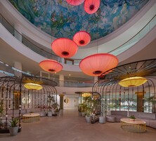 Um hall amplo com teto alto, luminárias pendentes vermelhas e um mural.