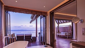 Uma casa de banho moderna com banheira, zona de duche e vista para a praia.
