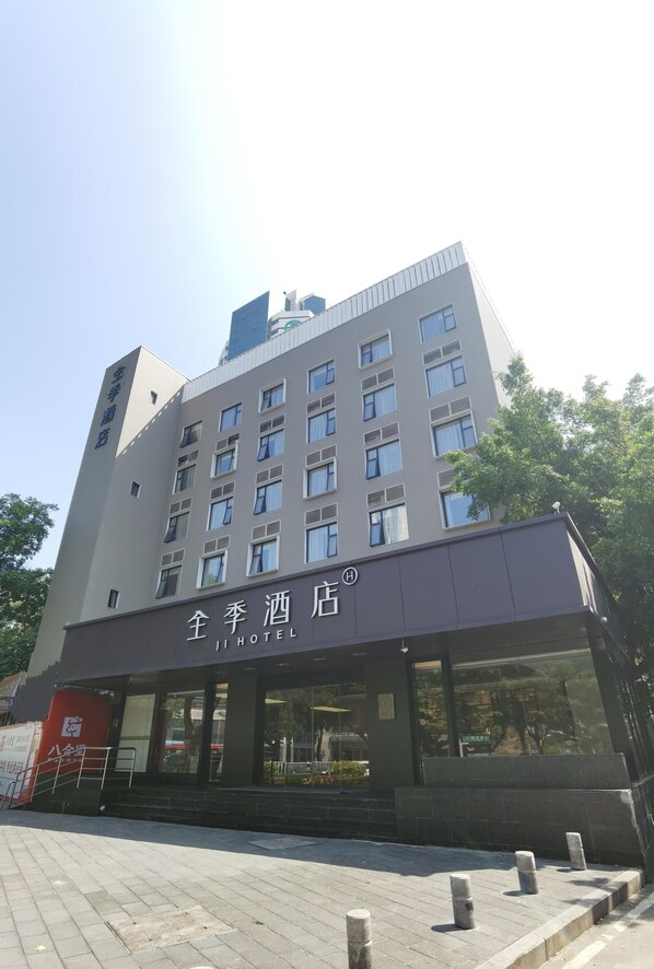 Um edifício de hotel com vários andares, janelas amplas e uma placa indicando ser um hotel.