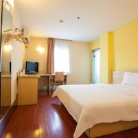 Quarto de hotel com cama, escrivaninha, cadeira, televisão e espelho.