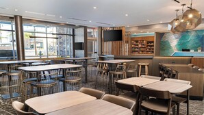 Um restaurante moderno com várias áreas de estar, um bar e uma grande tela de televisão.