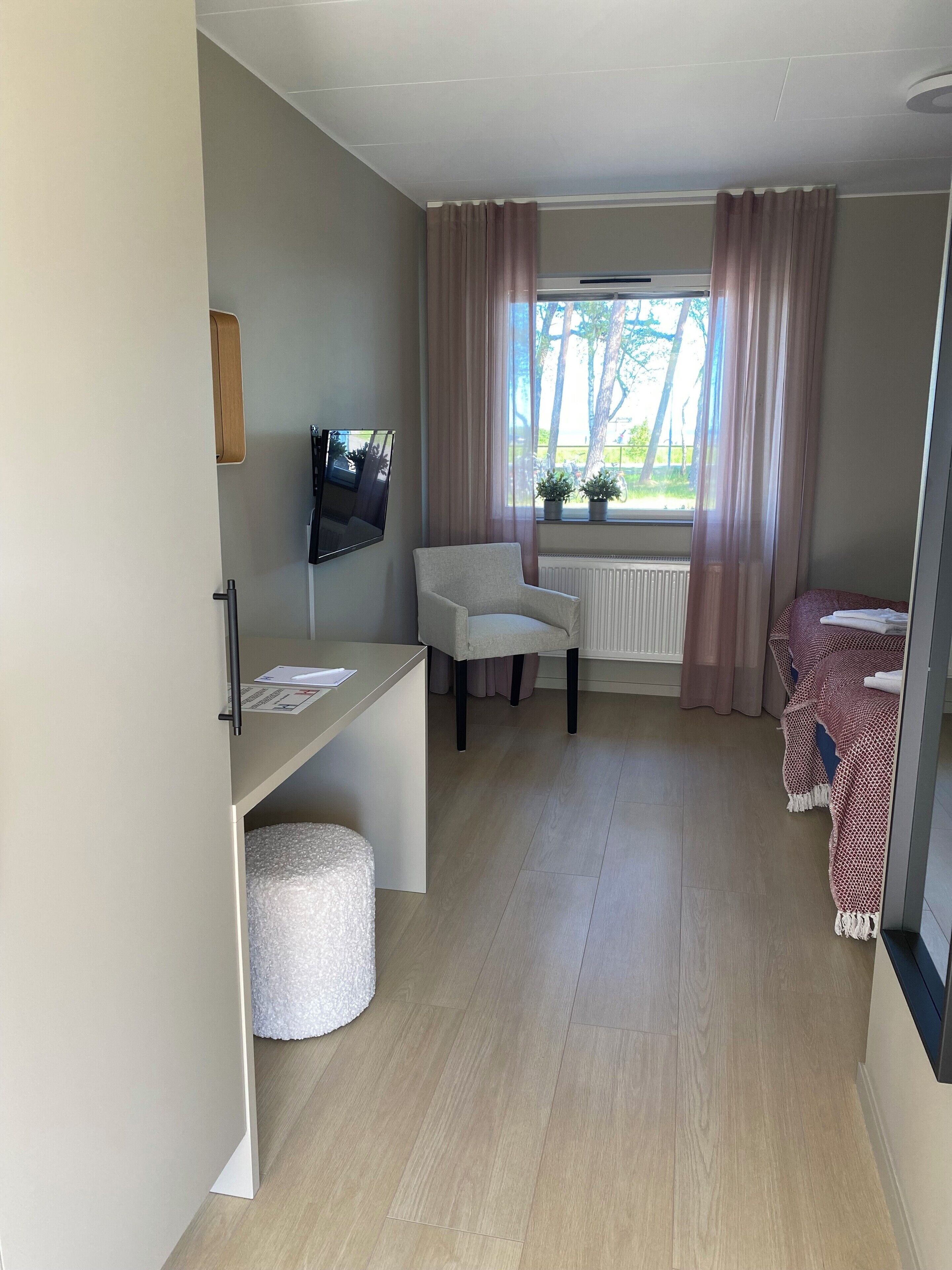 Quarto compacto com escrivaninha, cadeira e cama com manta estampada.