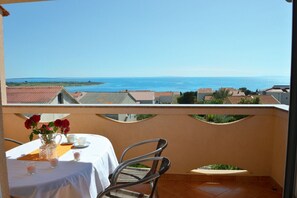 Varanda com mesa posta para dois, com vista para o litoral.