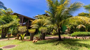 Um jardim exuberante com palmeiras, uma estrutura de madeira e um edifício verde.