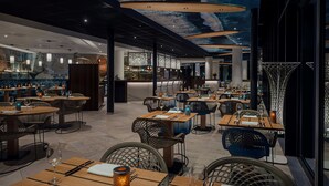 Restaurante moderno com tetos altos, iluminação ambiente e diversos tipos de assentos.
