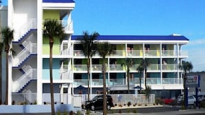 Um hotel com vários andares, varandas, um teto azul e palmeiras.