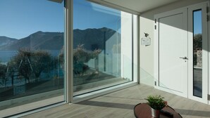 Quarto moderno com uma grande porta de vidro que dá para uma varanda com vista para as montanhas.