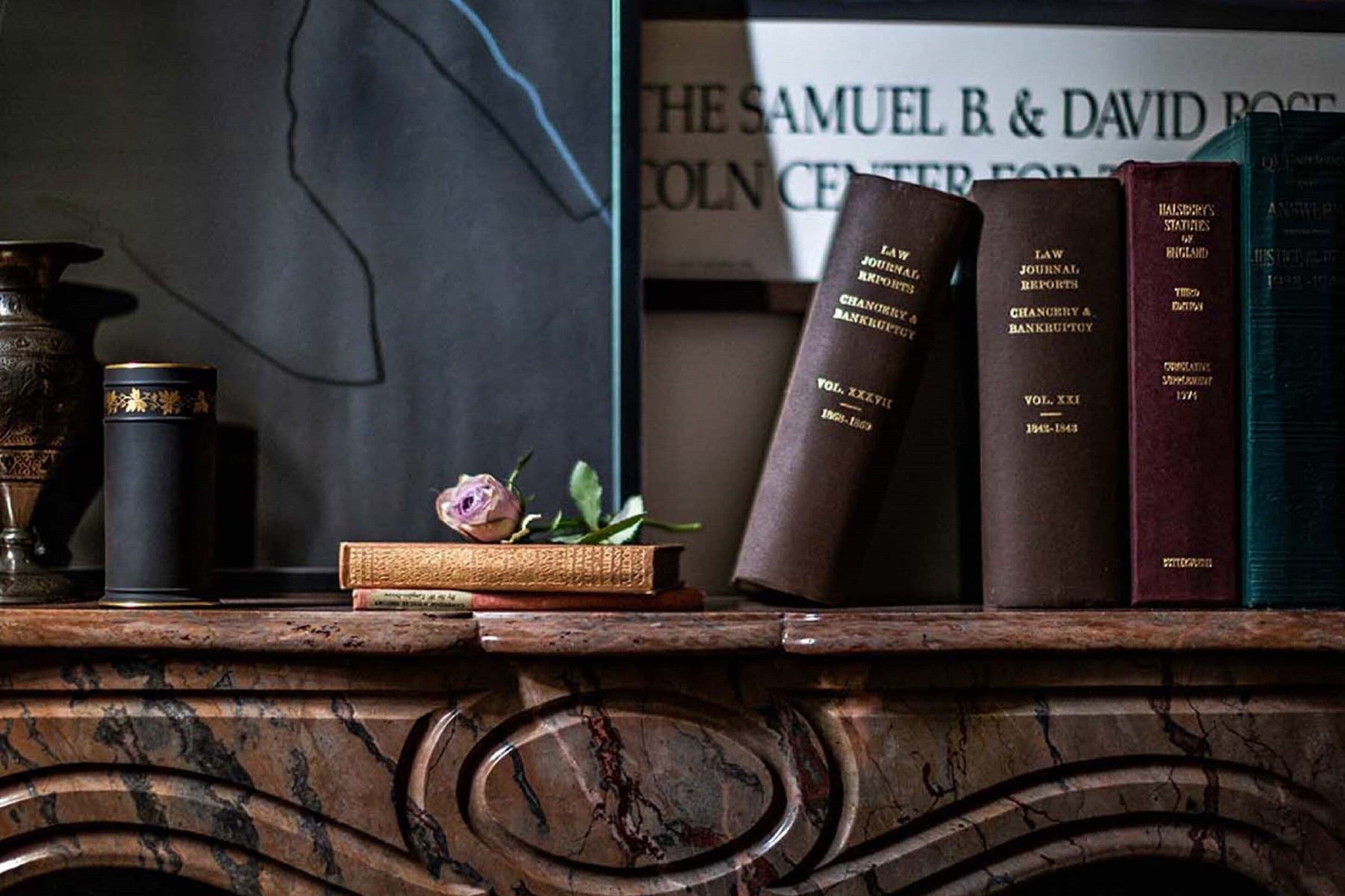 Uma mesa de mármore com livros, um vaso e um quadro emoldurado.