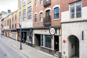 Uma fileira de edifícios com lojas, incluindo uma placa visível para 'Lofts St-Jo' e um hidrante na calçada.