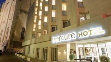 Um hotel com fachada moderna, entrada imponente e um edifício de pedra adjacente.