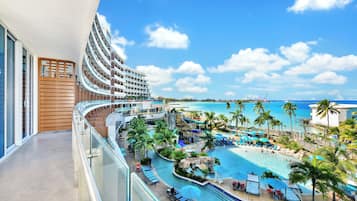 Varanda de hotel com vista para a área da piscina do resort, incluindo um toboágua e espreguiçadeiras.