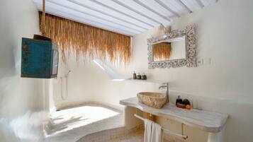 Uma casa de banho com banheira, toucador de madeira, espelho com moldura ornamentada e um porta-toalhas suspenso.