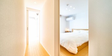Quarto de hotel com cama, mesa de cabeceira com luminária e luminária no teto.