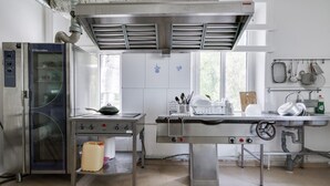 Uma cozinha comercial com eletrodomésticos de aço inoxidável, um fogão grande e uma pia.