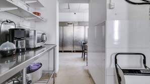 Cozinha moderna com eletrodomésticos de aço inoxidável, uma cafeteira e uma chaleira no balcão.