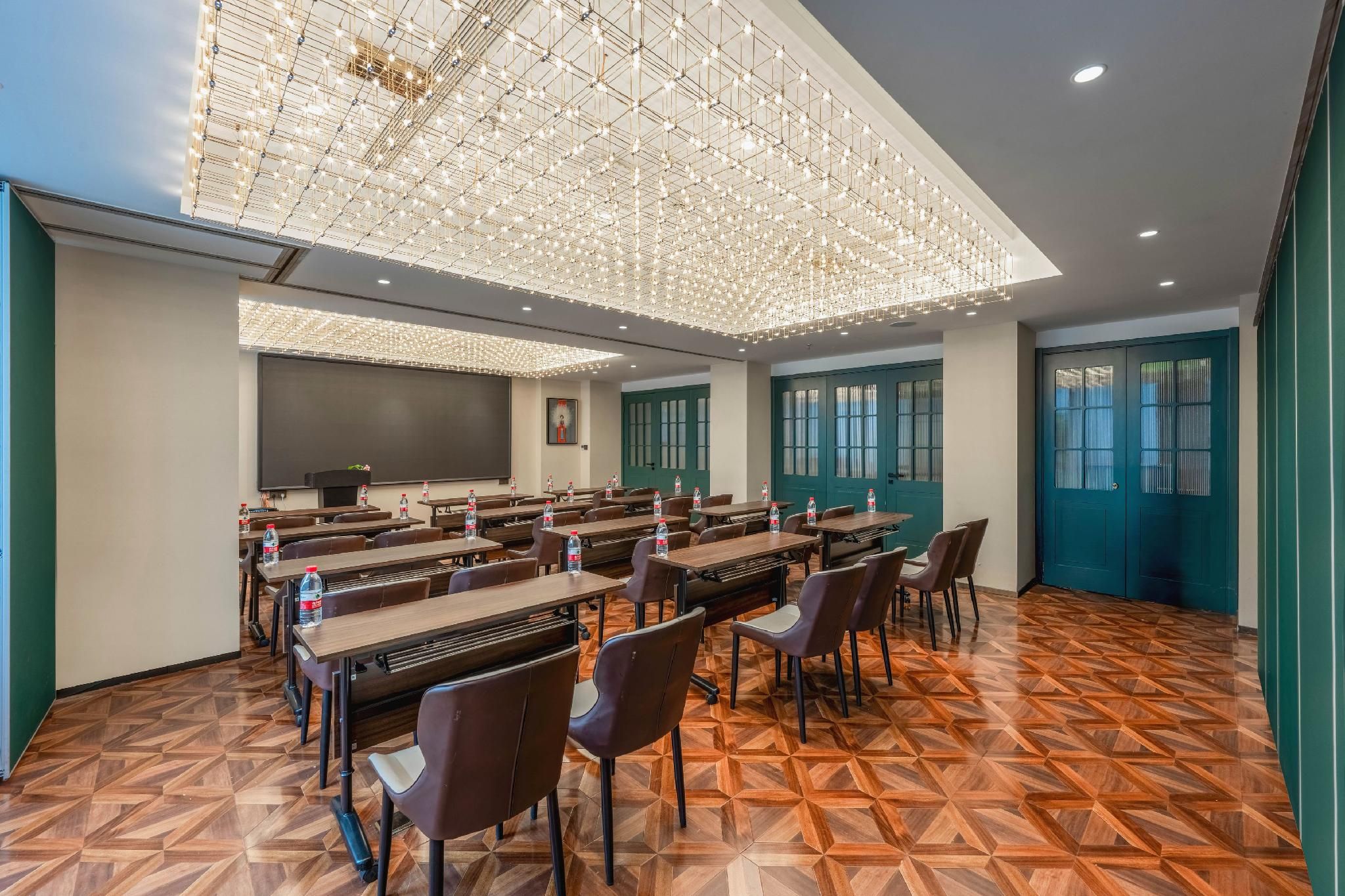 Uma sala de conferências com lustre moderno, mesas e cadeiras de madeira.
