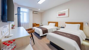 Quarto de hotel com duas camas, uma mesa, uma cadeira, uma televisão e uma janela com cortinas.