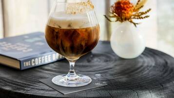 Um copo de café gelado sobre uma mesa de madeira, com um livro intitulado