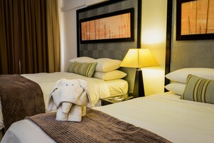 Quarto de hotel com duas camas, uma luminária e uma toalha sobre uma das camas.