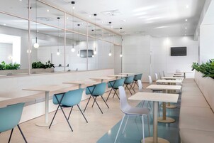 Uma área de jantar moderna com um balcão comprido, várias mesas e cadeiras.